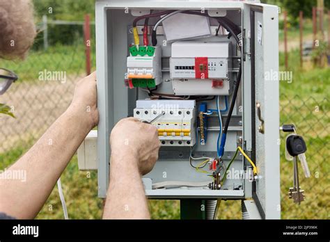 Electrician Fastens Connecting Strip To Fuse Box Using Phillips