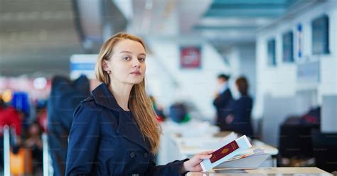 국제 공항의 체크인 카운터에서 경찰관에게 여권을 주고 탑승권을 기다리는 젊은 여성 사진 Unsplash의 여행 가방 이미지