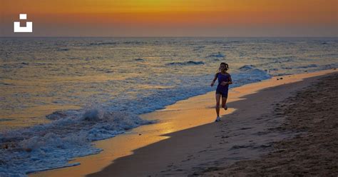 일몰 동안 해변에서 산책하는 검은 드레스를 입은 여자 사진 Unsplash의 무료 플라야 데 자호라 이미지
