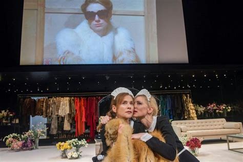 Two Women Sitting In Front Of A Large Screen
