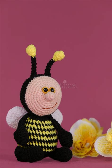 Amigurumi Bumblebee Doll On Pink Background Next To Yellow Orchid