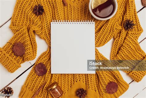 메모장의 아늑한 평평한 평지 레몬 차 컵 노란색 스웨터 잎 계피 스틱 과 흰색 나무 배경에 소나무 콘 텍스트 장소와 가을 구성