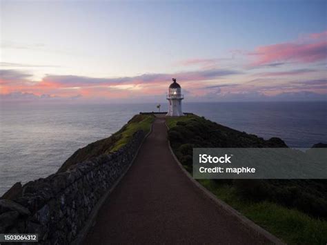 뉴질랜드 노스랜드의 절벽 꼭대기에 있는 유서 깊은 흰색 Cape Reinga 등대로 이어지는 보행자 아스팔트 도로 산책로 등대에