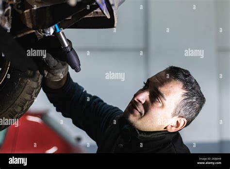 Male With Auto Torch While Removing Stripped Lug Nuts From Car During Repairing Process In