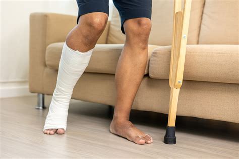 남자는 목발로 집에서 걷는 캐스트 넥 부목 칼라 슬링 지원 팔에 다리 부목으로 사고 골절 부러진 뼈 부상으로 고통을 겪습니다