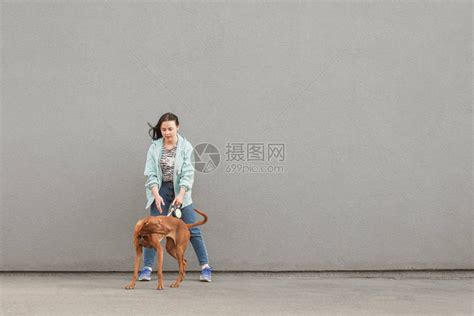 女人和一只顽皮的狗在街上散步高清图片下载 正版图片504574034 摄图网