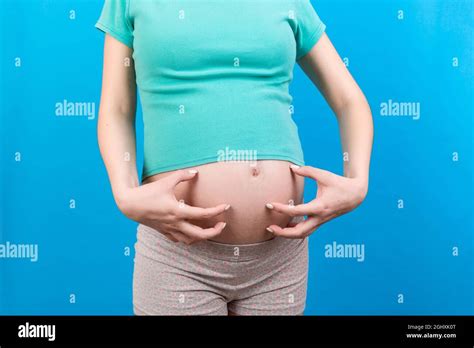 Pregnant woman scratching her belly on colored background Stock Photo - Alamy