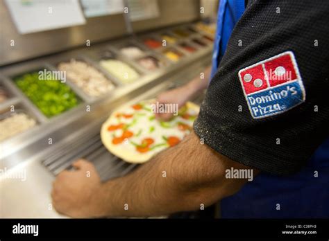 A Dominos Pizza Employee Preparing A Fresh Pizza Ready For The Cooking