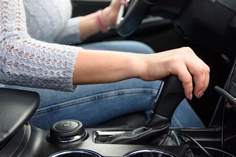 여성 운전자가 차를 운전하고 있습니다 그녀는 움직이기 전에 자동 기어박스에서 기어를 옮기고 있습니다 청바지와 스웨터를 입은 젊은