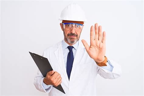 高級工程師男子戴著頭盔眼鏡拿著剪貼簿在孤立的白色背景與張開的手做停止標誌與認真和自信的表情防禦手勢 照片檔及更多 剪貼板 照片 剪貼板