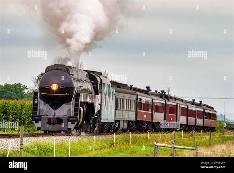 A Vintage Steam Locomotive Is Chugging Along A Railway Track Emitting