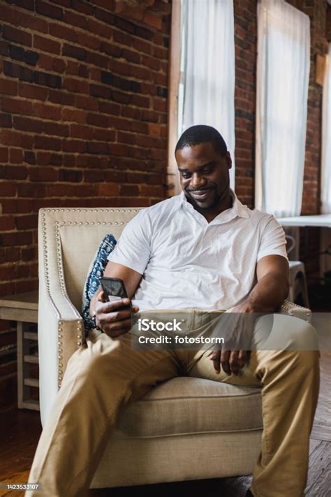 안락 의자에 앉아서 스마트 폰에서 재미있는 비디오를 보는 즐거운 중년 남자 40 44세에 대한 스톡 사진 및 기타 이미지 40 44세 거실 긍정적인 감정 표현