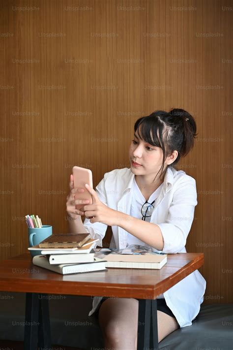 캐주얼한 옷을 입은 젊은 여자가 카페에 앉아 휴대폰을 사용하는 초상화 사진 Unsplash의 사업 이미지