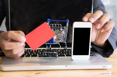 남자는 신용 카드와 모바일 스마트 전화와 슈퍼마켓을 보여주는 온라인 쇼핑을 위한 노트북 컴퓨터에 트롤리 카트 사업가 인터넷에서 상품을 구입 남자는 은행 웹사이트에 납부금