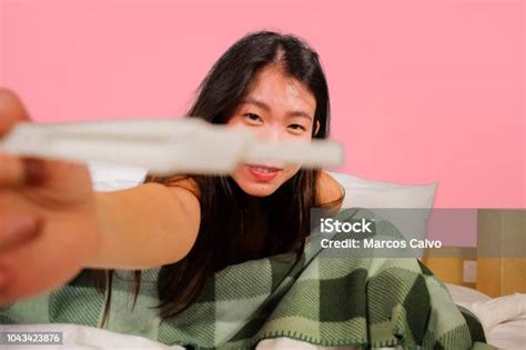 젊은 행복 하 고 흥분 아시아 한국 여성 임신 테스트 검사를 들고 침대에 놀란 황홀 하 고 즐거운 기대 아기 축복 느낌의 기