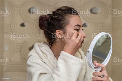 아름다운 어린 소녀는 화장실에서 거울에 그녀의 얼굴에 기초를 적용합니다 건강한 생활방식에 대한 스톡 사진 및 기타 이미지