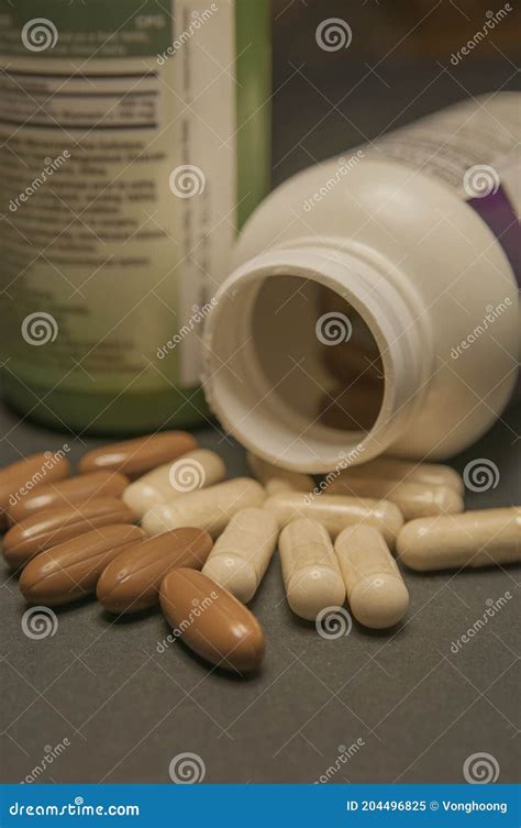 2 Bottles Of Plastic Pill Container And Brown And White Capsules Pills