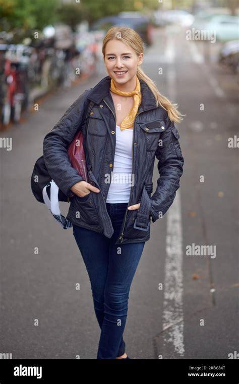 Portrait Of Young Blond Woman In City Street Holding Hands In Her