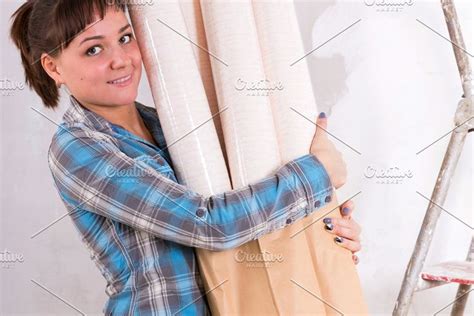 Pretty Woman Repairing Wallpaper With Roller Paste