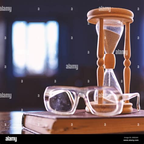 Hourglass Old Book And Eyeglasses On Wooden Table Dark Background