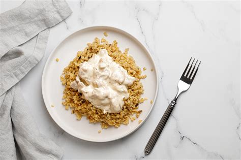 닭고기와 크림 소스를 곁들인 벌거 벌거 죽과 치킨 필레와 저녁 식사 아이디어 흰색 배경과 흰색 접시 맨 위 보기입니다 0명에