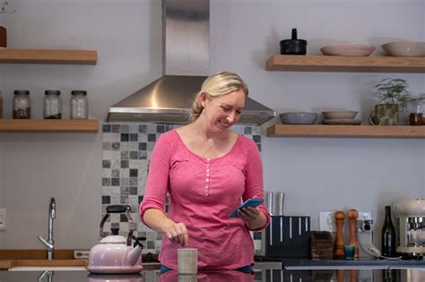 여자는 차 한 잔을 만드는 동안 그녀의 휴대 전화에서 테이크 아웃 음식을 주문 35 39세에 대한 스톡 사진 및 기타 이미지 35 39세 Brand Name Smart