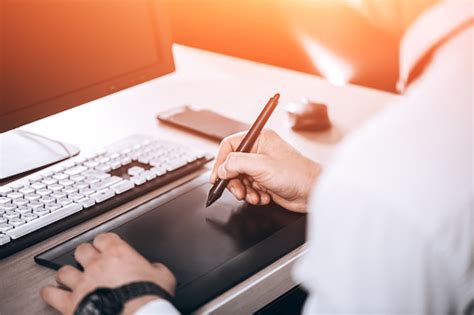 그래픽 디자이너의 작업 영역입니다 펜 태블릿에 손 똑똑한 젊은이 사무실에서 무료 검은 모니터 복사 공간 디자인에 대 한입니다 태양 빛의 따뜻한 섬광 개념에 대한 스톡 사진