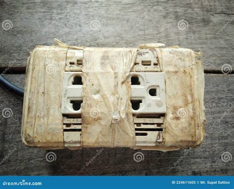 Old Power Socket Wrapped With White Masking Tape Deteriorated Placed On A Wooden Floor Giving