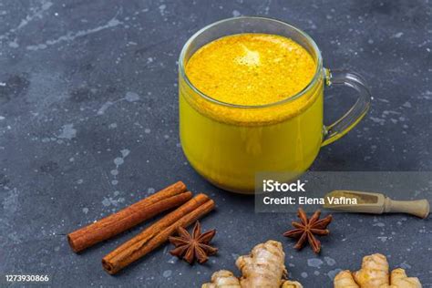 전통적인 인도 음료 심황 우유는 심 황과 뿌리 생강 계피 어두운 배경에 아니스 별 유리 머그잔에 황금 우유입니다 체중 감량 건강하고 유기농 음료 닫기 텍스트에 대한 공간을