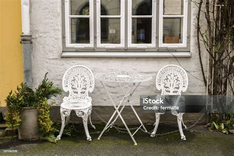 독일 루벡의 구시가지에 있는 유서 깊은 집 정면 앞 보도에 흰색 색칠된 철의자와 장식용 빈티지 장식장식이 있는 접이식 테이블 0명에 대한 스톡 사진 및 기타 이미지 Istock