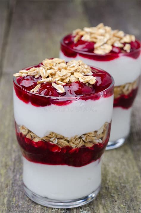 Postre Acodado Con El Yogur El Granola Y La Cereza En La Madera Foto
