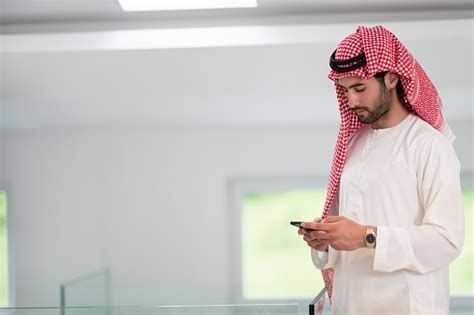 젊은 현대 무슬림 아라비아 사업가들은 집에서 스마트 폰을 사용하는 동안 전통적인 옷을 입고있다 고품질 사진 20 24세에 대한 스톡 사진 및 기타 이미지 Istock