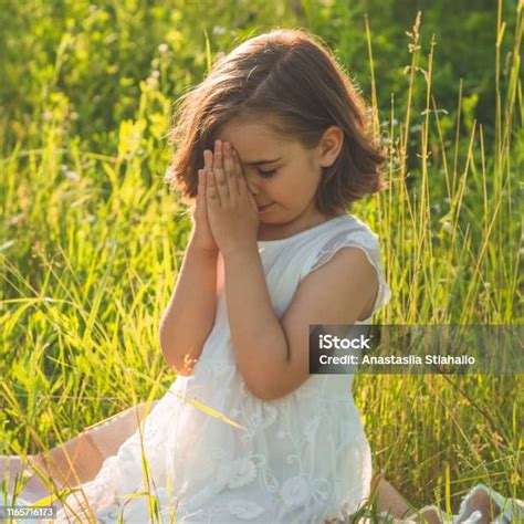 어린 소녀는 아름다운 일몰 동안 들판에서기도 그녀의 눈을 감고 손은 믿음 영성 및 종교를 위한 기도 개념으로 접혀 있었다 평화 희망 개념에 대한 스톡 사진 및 기타 이미지