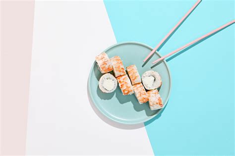젓가락이 달린 세라믹 접시에 새우를 곁들인 마키 롤 컬러 배경에 필라델피아 치즈와 새우 초밥 롤 일본어 메뉴 컨셉 새우 초밥은