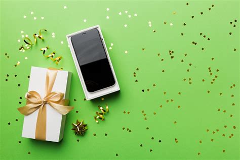 골드 리본과 스마트폰이 있는 기프트 박스를 컬러 배경 상단 보기로 오픈했습니다 빈 오픈 박스 포장 모형 디자인템플릿 브랜딩 모형