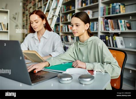 A Redhead Tutor Teaches A Teenage Girl In A Library Working On A