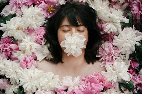 분홍색 모란에 누워 입에 흰 모란과 아름 다운 갈색 머리 소녀 향기와 치료 개념입니다 국제 여성의 날입니다 크리에이 티브 아트