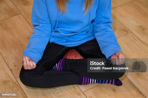 A Woman Sitting Crosslegged On A Sofa With Her Legs Tangled And Her