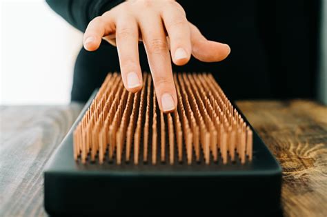 나무 테이블에 구리 손톱이있는 어두운 오크로 만든 Sadhu 보드 소녀는 구리 손톱 위로 손가락을 움직입니다 손톱에 서있는 요가 연습 건강한 생활방식에 대한 스톡 사진 및