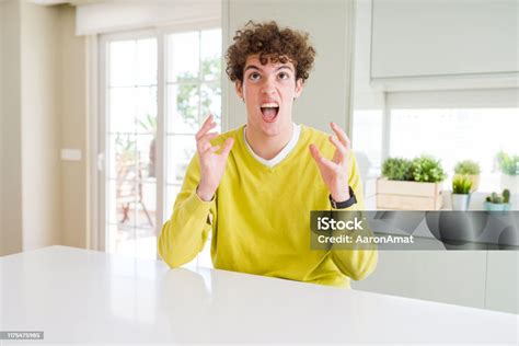 집에서 노란 스웨터를 입은 젊은 잘생긴 남자는 미친 미친 소리와 공격적인 표정과 팔을 들고 고함쳤다 좌절 개념입니다 가정 생활에 대한 스톡 사진 및 기타 이미지 Istock