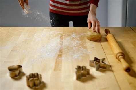 Premium Photo Woman Sprinkles Flour On Table To Roll Out Dough