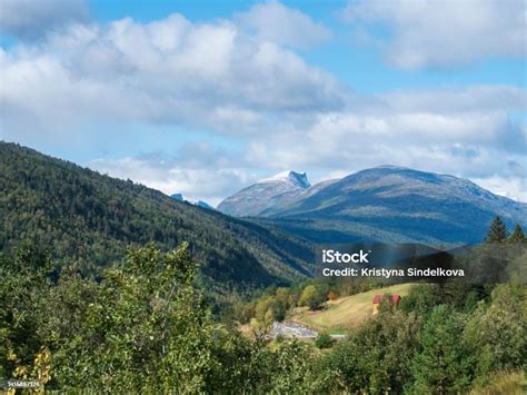 도로 E136에서 롬스 달렌 계곡을 바라 볼 수 있으며 눈 덮인 산 녹색 숲 및 작은 붉은 노란 집이있는 봉우리 푸른 하늘 흰 구름 배경 0명에 대한 스톡 사진 및 기타