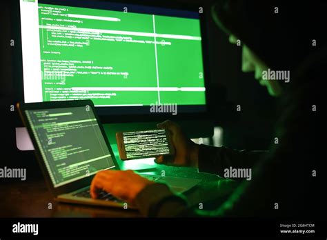 Hacker With Mobile Phone Using Computer In Dark Room Stock Photo Alamy