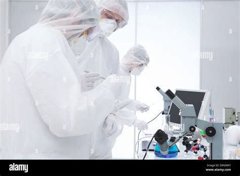 Close Up Of Three People Manipulating Lab Tools In A Chemistry Lab Around A Lab Table Stock