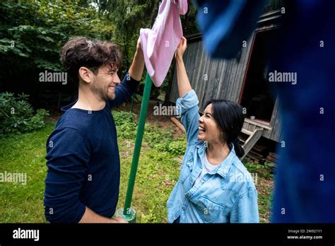 Happy Man And Woman Holding Pink Cloth Drying In Front Of Log Cabin Stock Photo Alamy