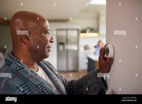 Mature Man Turning Control Dial On Digital Central Heating Thermostat At Home Stock Photo Alamy