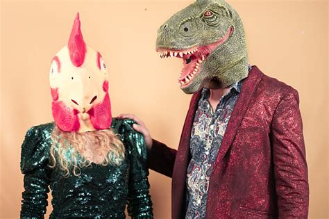 T렉스 공룡과 치킨 마스크를 착용 커플 미친 친구는 파티를 축하하는 재미를 가지고있다 터무니없고 초현실적 인 재미있는 개념 노란색 배경입니다 공룡에 대한 스톡 사진 및 기타