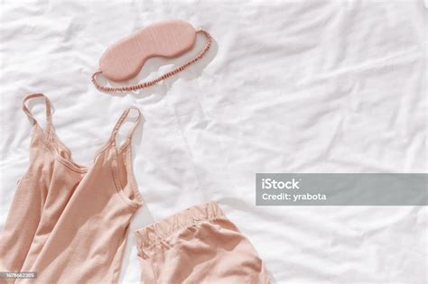 베이지색 잠옷과 아이 마스크는 하얀 침대 보를 배경으로 공간을 복사한다 밤에는 편안한 휴식을 위한 아늑한 잠옷 싱글 렛 반바지