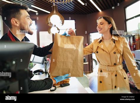 Shop Assistant Handling Shopping Bag To Female Customer In Grocery