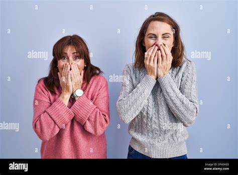 Mother And Daughter Standing Over Blue Background Laughing And